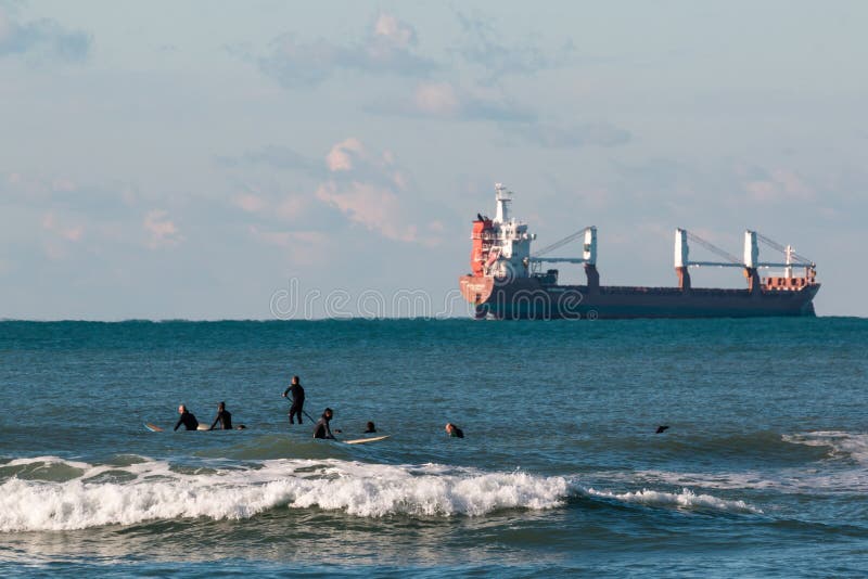 Surfers Waiting for Waves, Cargo Ship in Background Editorial ...
