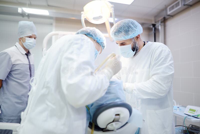 Surgeons and Nurse during a Dental Operation. Anesthetized Patient in ...