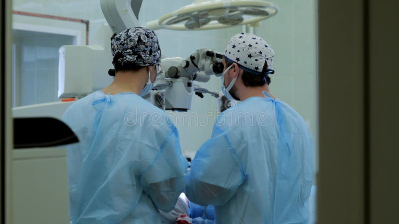 Surgeons Perform a Complex Operation Using a Microscope Stock Footage ...