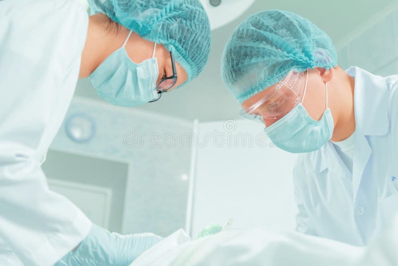 Two Surgeons Looking Down and Working at the Operating Table, Dark ...