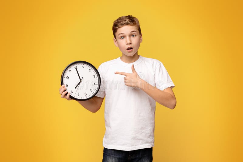 Surprised Boy Holding Clock Against Yellow Background Stock Photo ...