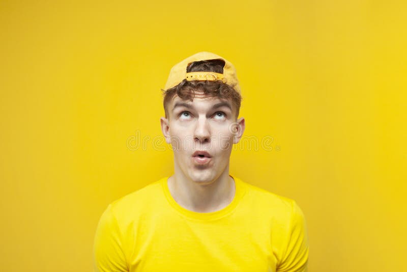 Surprised Guy in a Yellow Cap and T-shirt Looks Up Stock Photo - Image ...