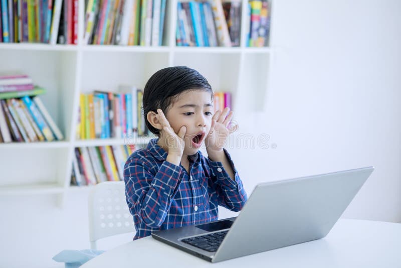 Surprised Little Boy Using a Laptop in the Library Stock Photo - Image ...