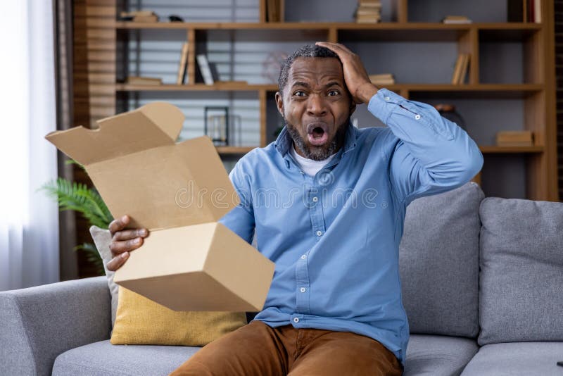 Surprised Man Sitting on Sofa Holding an Empty Box at Home Stock Image ...