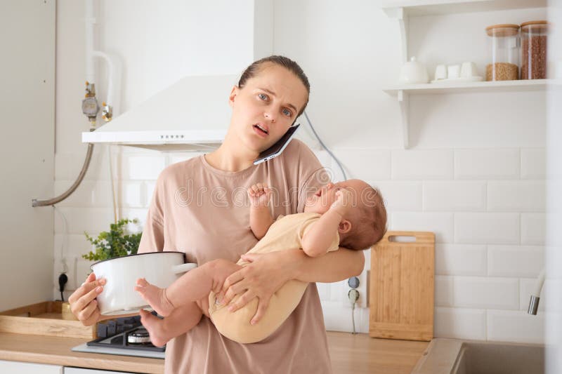 Surprised Mother Multitasking in Kitchen Holding Her Newborn while ...