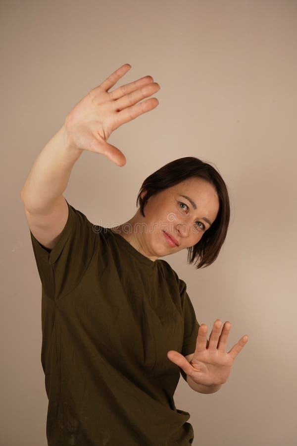 A Surprised Woman Stands by the Wall, with Her Hand Extended Forward ...