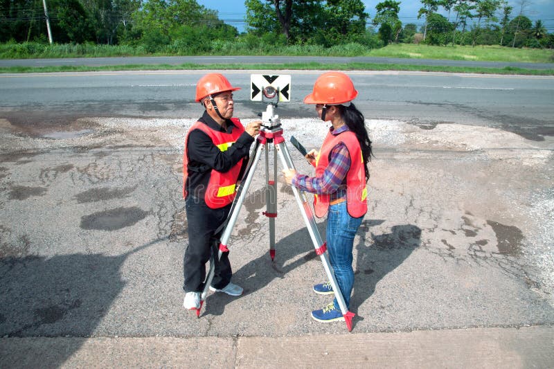 Surveyor or Engineer Setting Prism Reflector with Partner on the Field ...