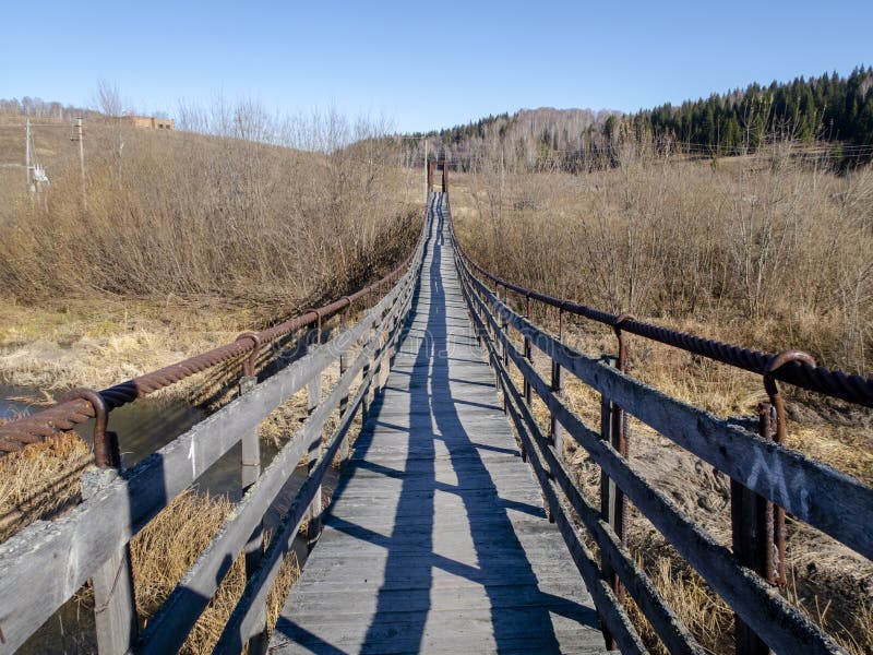 Suspension Bridge on Iron Cables Across the Autumn Valley with a Small ...
