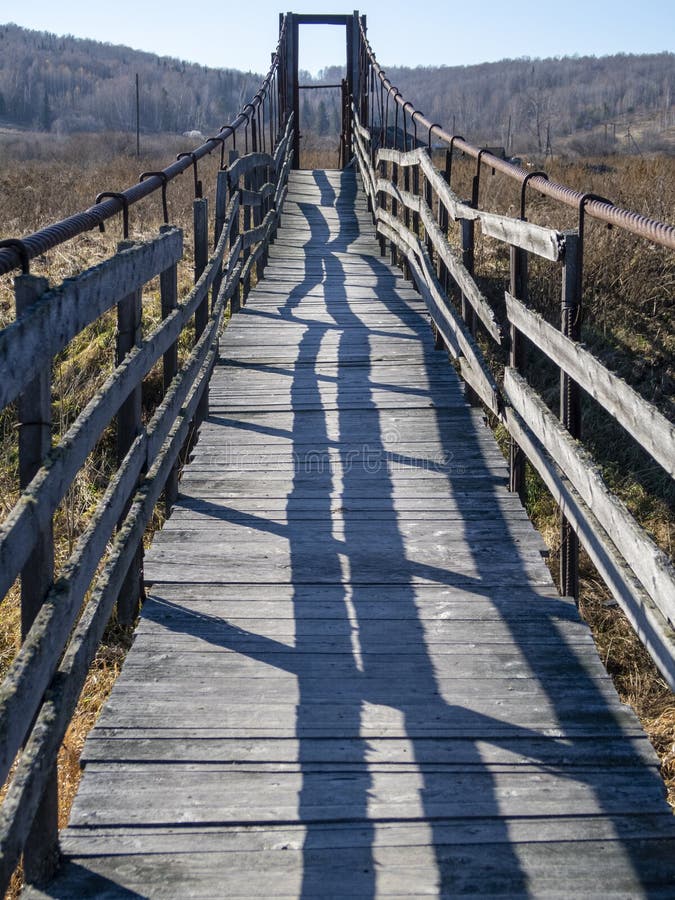 Suspension Bridge on Iron Cables Across the Autumn Valley with a Small ...