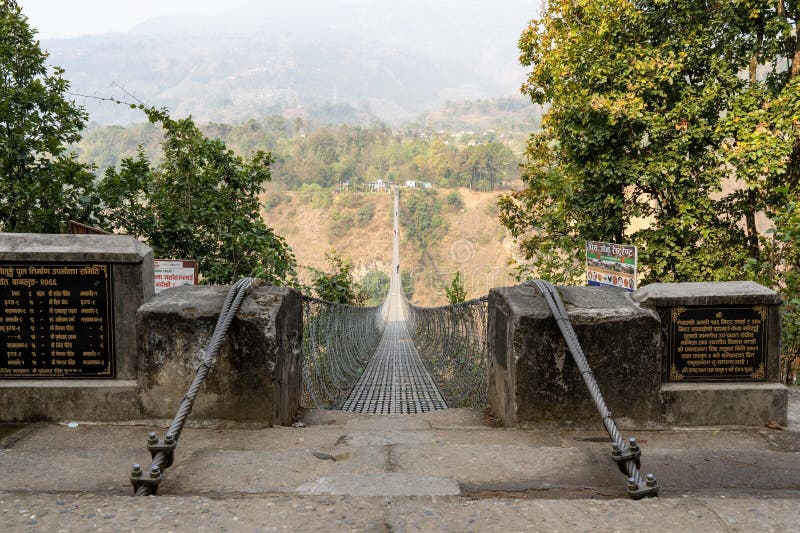 A Suspension Bridge in Front of a Mountain and Trees in the Background ...