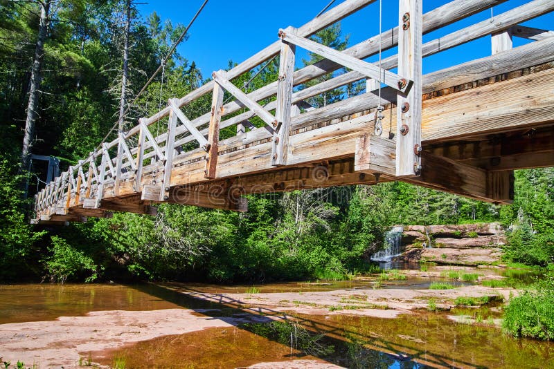 Suspension Bridge from Side Over Brown River with Waterfall in ...