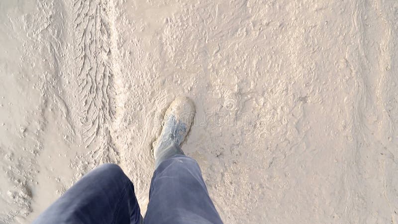 The Swamp at a Construction Site. Men`s Feet in Rubber Boots are in the ...