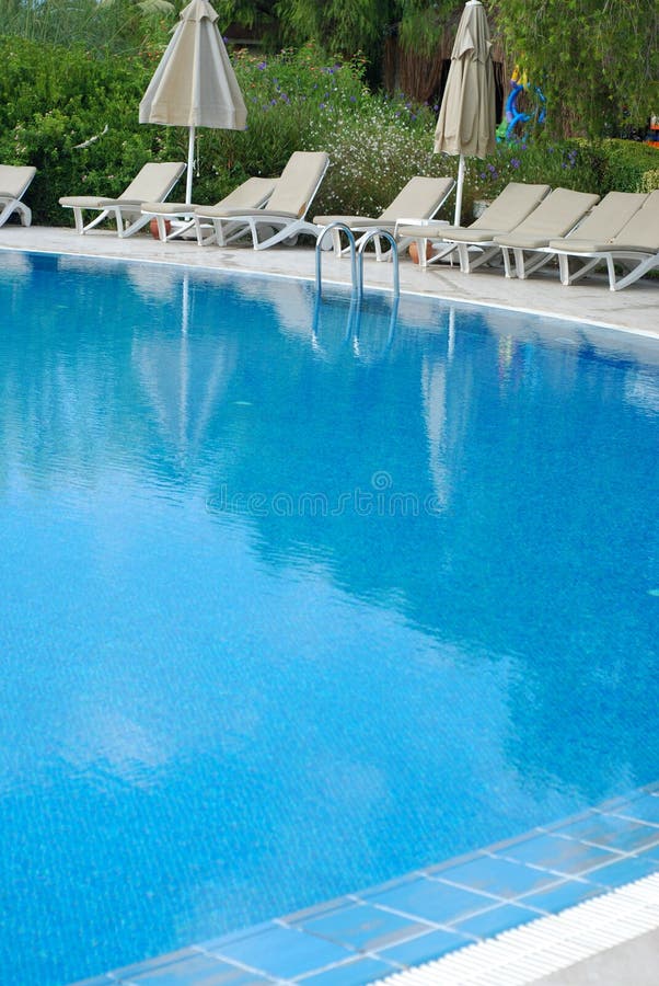 Sweeming Pool with Blue Water with Sun Umbrella and Seetings. Vertical ...