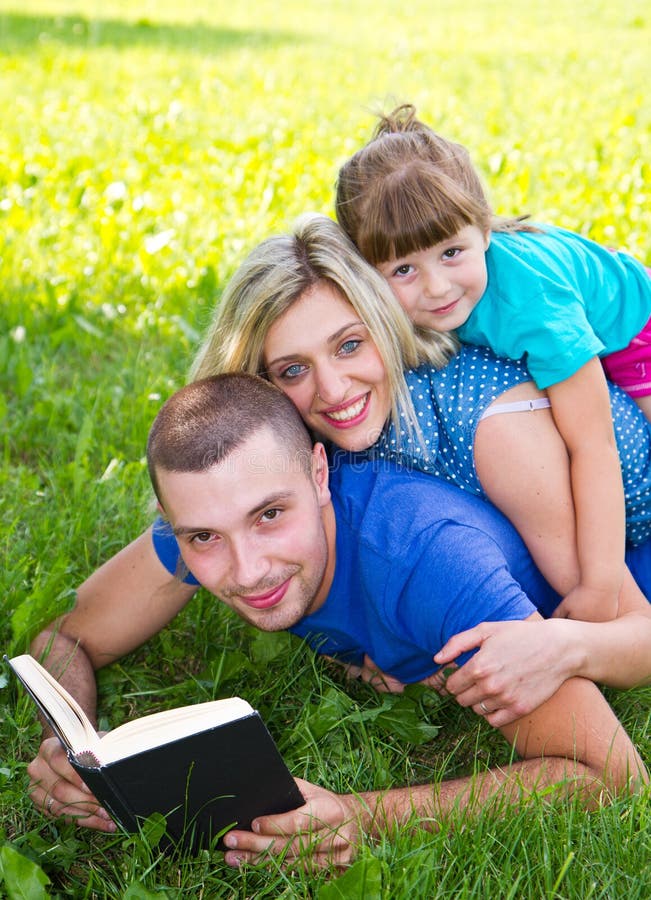 Sweet Family Reading a Book on the Green Grass Stock Image - Image of ...