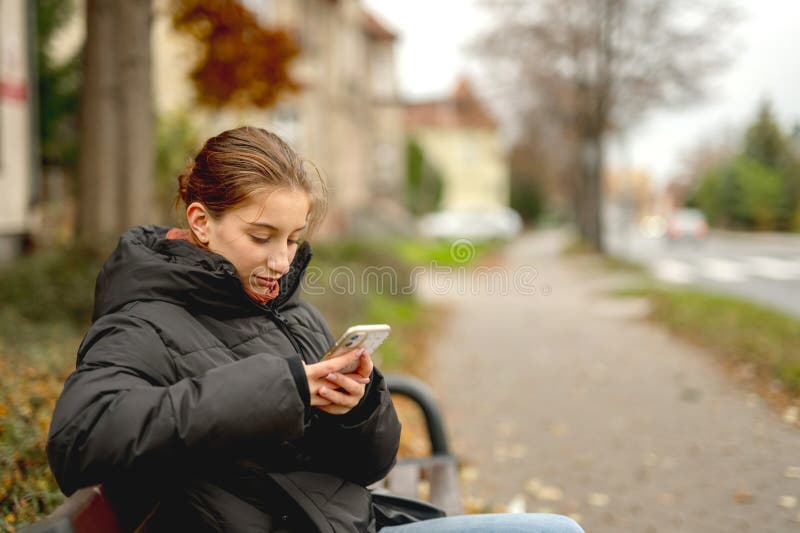 Sweet Girl Scrolling Phone while Sitting on Bench Stock Photo - Image ...
