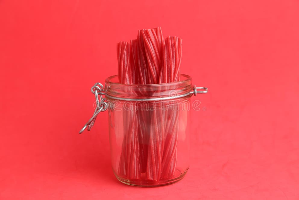 Sweet Red Candy Sticks in the Glass Jar on the Red Surface Stock Photo ...