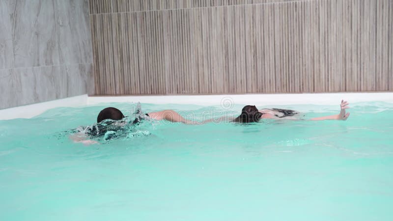 Swimming Lesson Instructor Guides Beginner in Pool Skills and ...