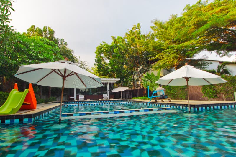 Swimming pool among garden stock image. Image of umbrella - 98170289