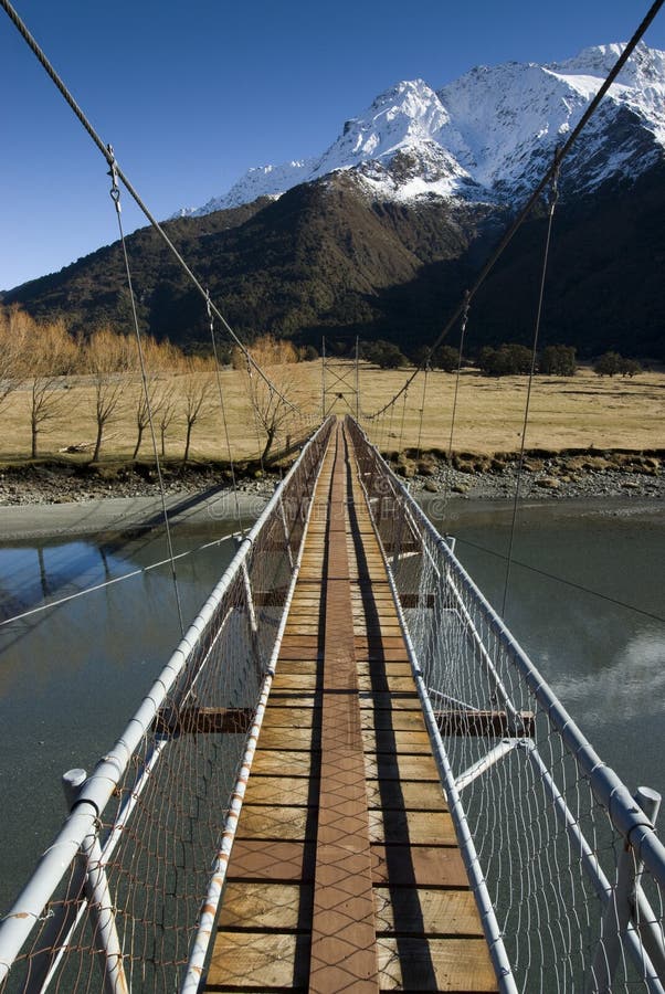 Swing Bridge Crossing To Snow Capped Mountains Stock Photo - Image of ...