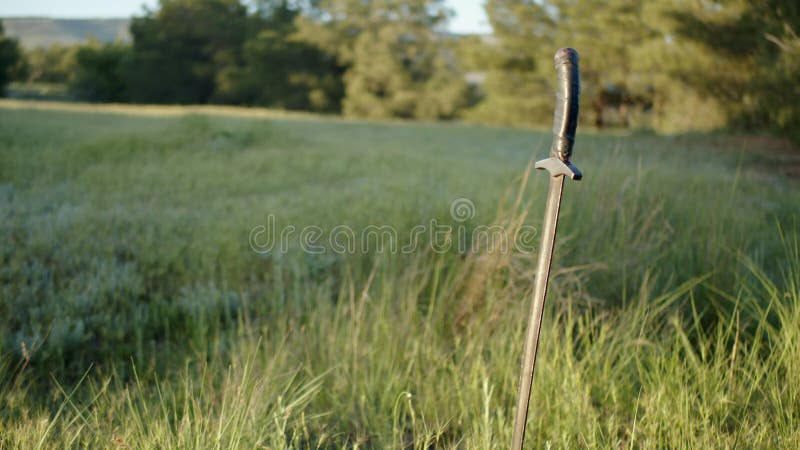 A Sword with a Handle Wrapped in Leather is Stuck in the Ground at the ...