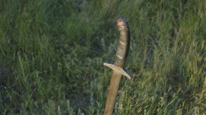 A Sword with a Handle Wrapped in Leather is Stuck in the Ground at the ...