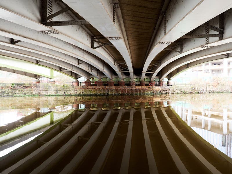 Symmetrical View Beneath a Bridge with Reflective Water Surface Stock ...