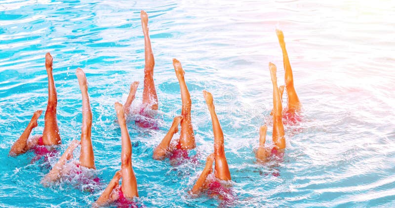 Synchro Swimmers Perform an Elegant Routine in a Bright Blue Pool Under ...