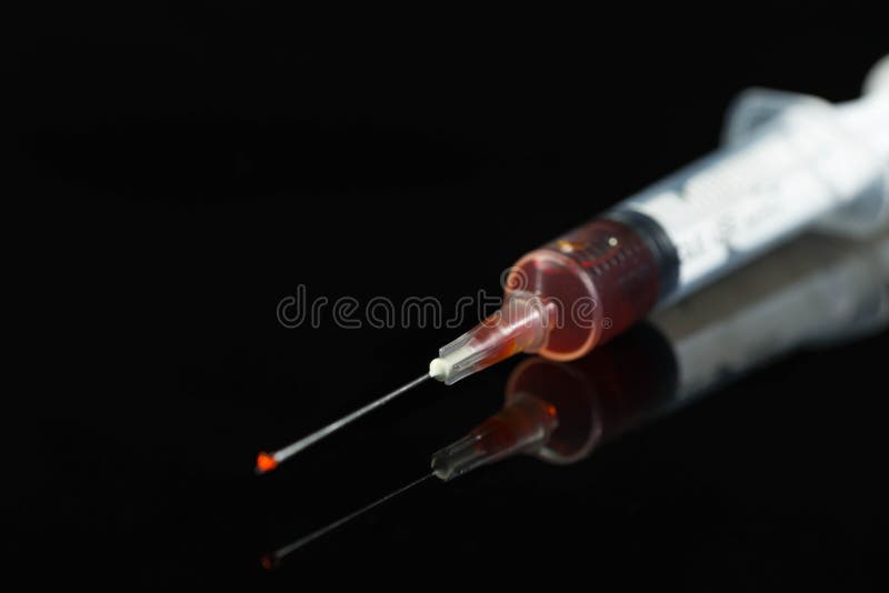 Syringe Filled with Red Liquid on Shiny Dark Surface Stock Photo ...