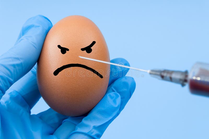 The Syringe is Injected into the Egg Close-up on a Blue Background. the ...