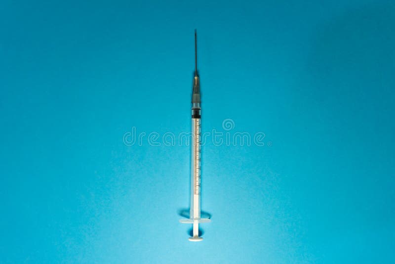 A Syringe with Its Needle Uncapped, in the Center of a Blue Background ...