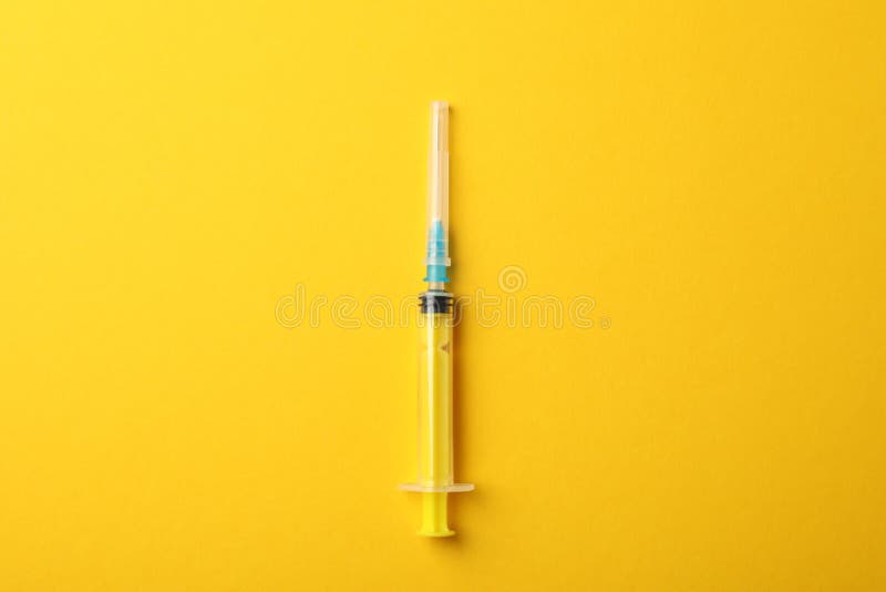A Syringe with a Yellow Substance and in the Background Four Test Tubes ...