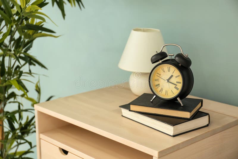 Table with Books and Alarm Clock Near Color Wall Stock Image - Image of ...