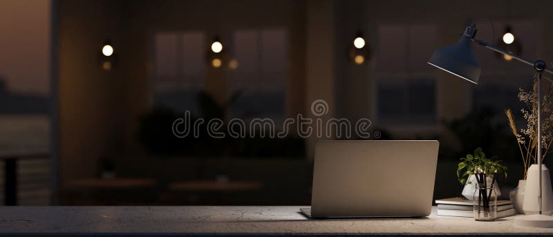 A Table Features a Laptop Computer and a Dim Light from a Lamp in a ...