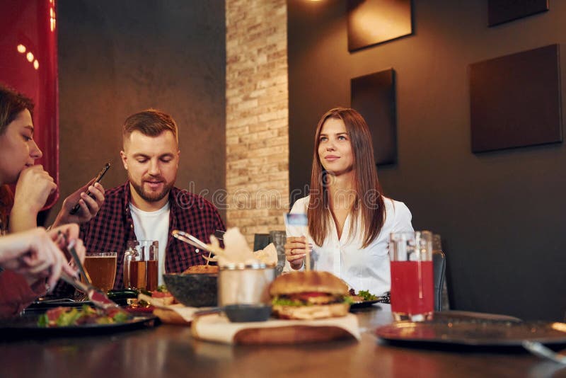 By the Table. Group of Young Friends Sitting Together in Bar with Beer ...