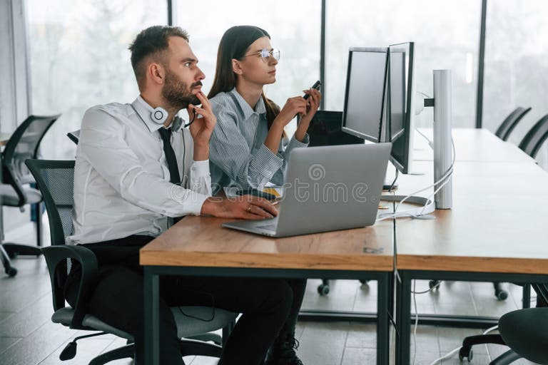 By the Table with Laptop. Two Employees are Working in the Office ...