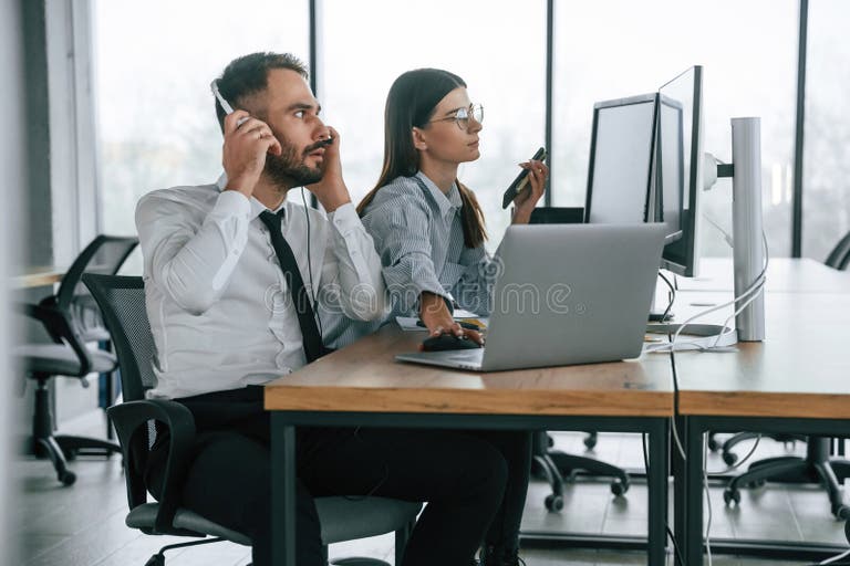 By the Table with Laptop. Two Employees are Working in the Office ...