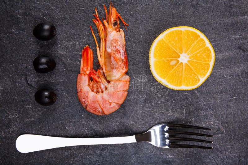 On the Table is Royal Prawn, Slice of Lemon, a Few Olives and a Fork ...
