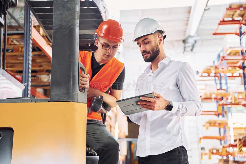 With Tablet and Cargo Moving Transport. Two Storage Workers is in the ...