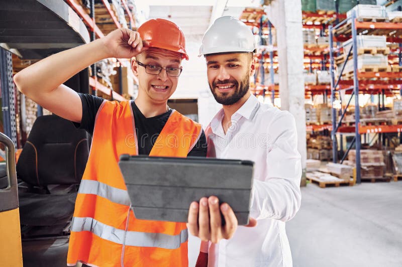 With Tablet and Cargo Moving Transport. Two Storage Workers is in the ...