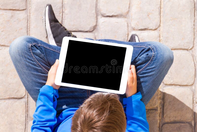 Tablet Computer in the Hands of a Child Who Sitting on the Ground ...