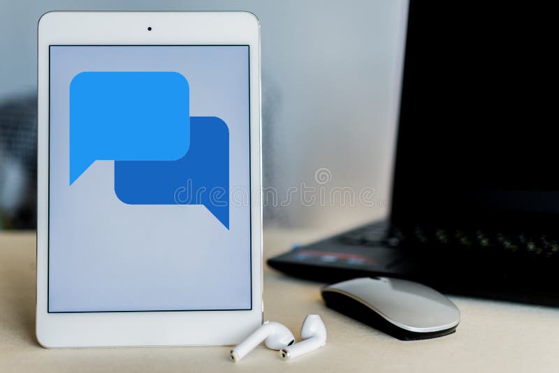 Tablet with Dialogue Icon on Its Screen Next To a Laptop on a Desk ...