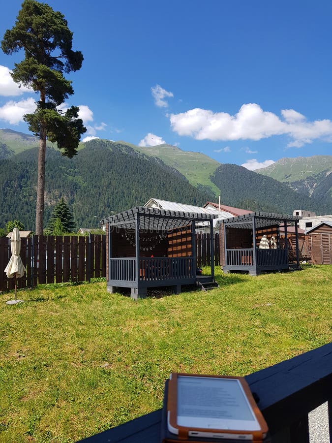 Tablet E-book in Nature Against the Backdrop of Mountains and Arbors ...