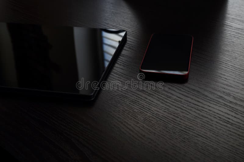 Tablet and Mobile Phone Lying on the Table in the Dark Stock Photo ...