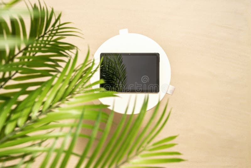 Tablet on the Table on the Sand of Beach Under Palm Trees Branch. Copy ...