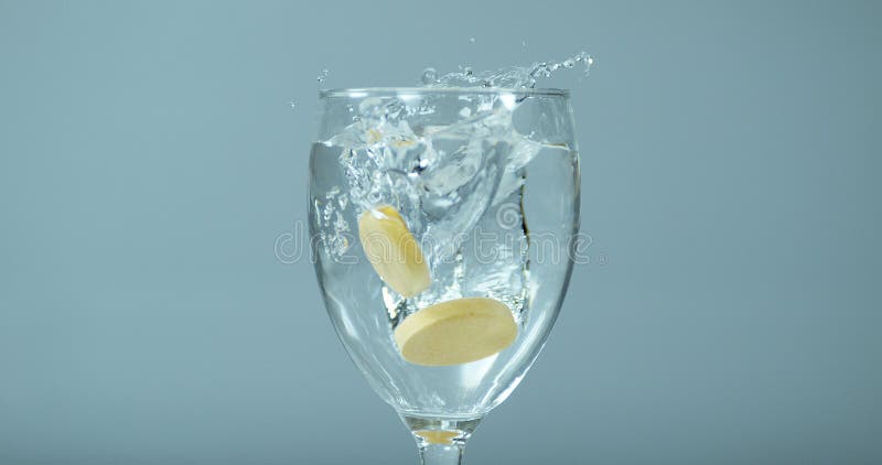 Tablets Falling and Dissolving into a Glass of Water Against White ...