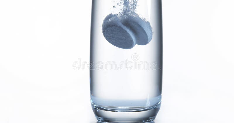Tablets Falling and Dissolving into a Glass of Water Against White ...