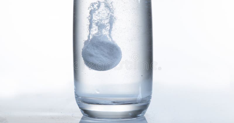 Tablets Falling and Dissolving into a Glass of Water Against White ...