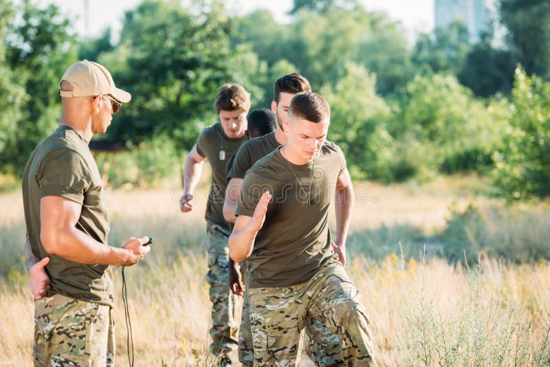 Tactical Instructor with Stop Watch Examining Multiracial Soldiers ...