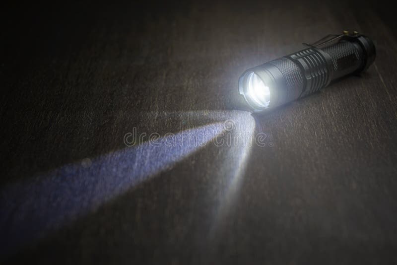 Tactical Waterproof Flashlight. LED Flashlight Shines on the Table in ...