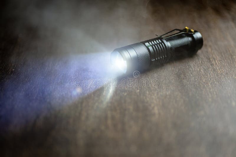 Tactical Waterproof Flashlight. LED Flashlight Shines on the Table in ...